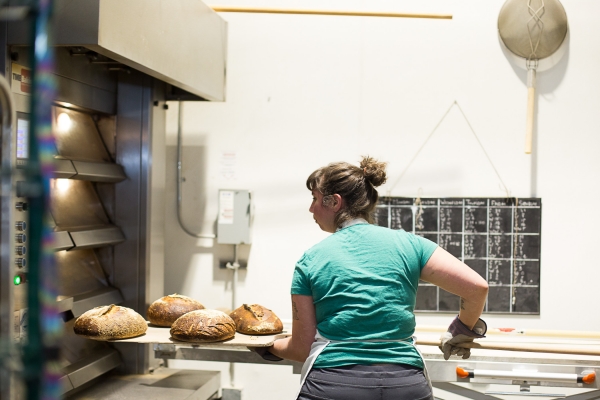 As Kneaded Bakery owner Iliana Berkowitz moves bread from the oven in ...